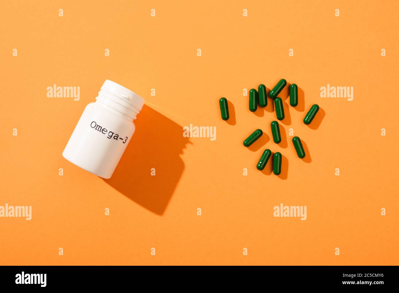 Top view of container with omega-3 lettering and green capsules on ...