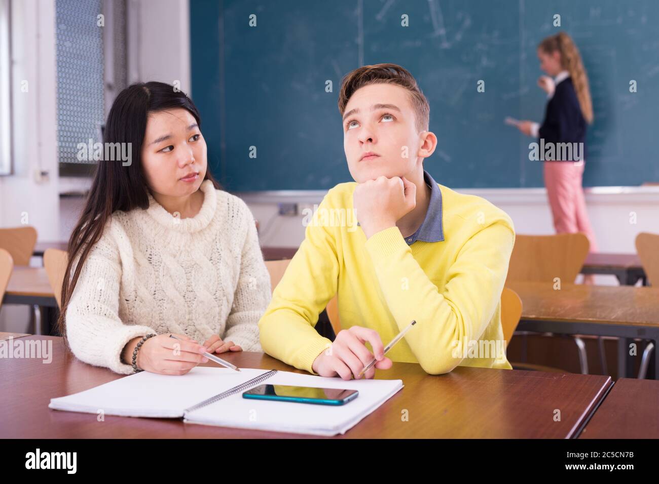 Chinese teen girl student trying to explain learning material to bored ...