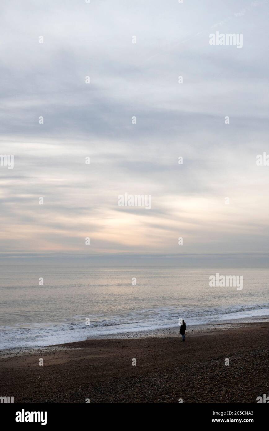 A Single Person Standing On The Beach Looking Out To Sea In The Evening ...