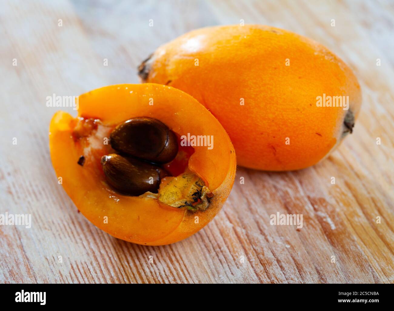 Whole and half fresh yellow loquat on wooden table. Healthy vegetarian ...