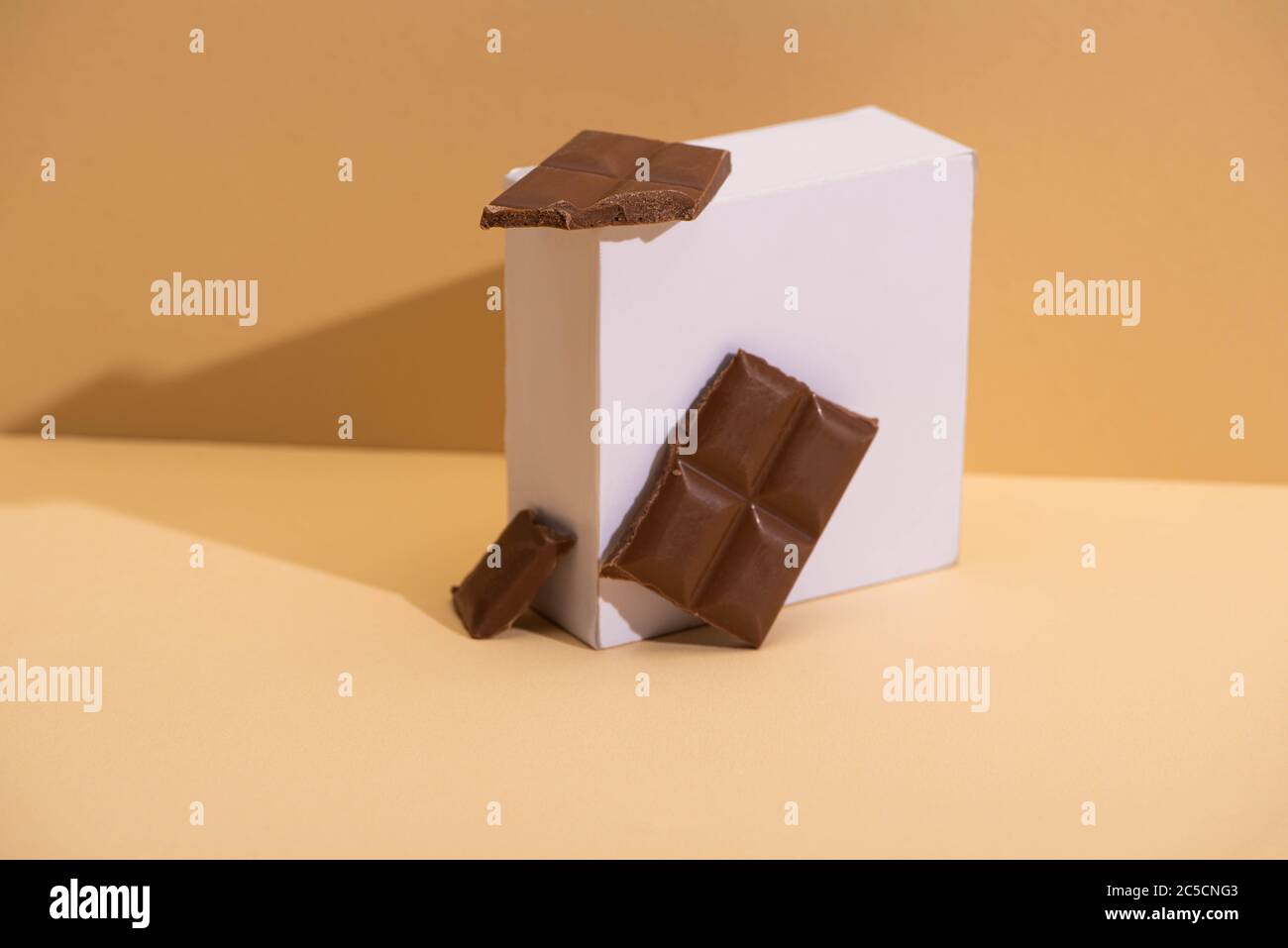 delicious milk chocolate pieces and square cube on beige background ...