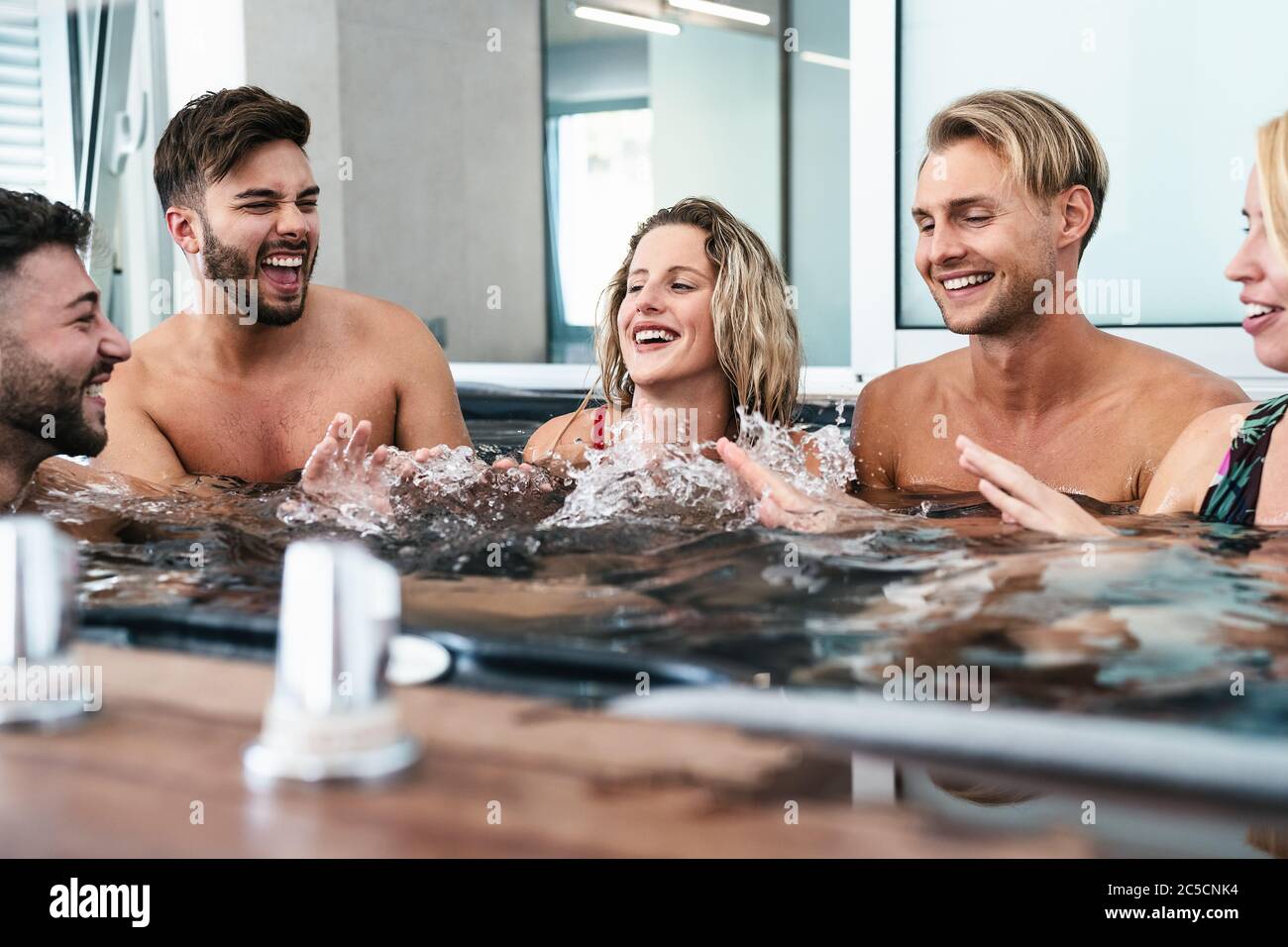 Happy friends enjoying vacations in jacuzzi luxury house - Young people ...