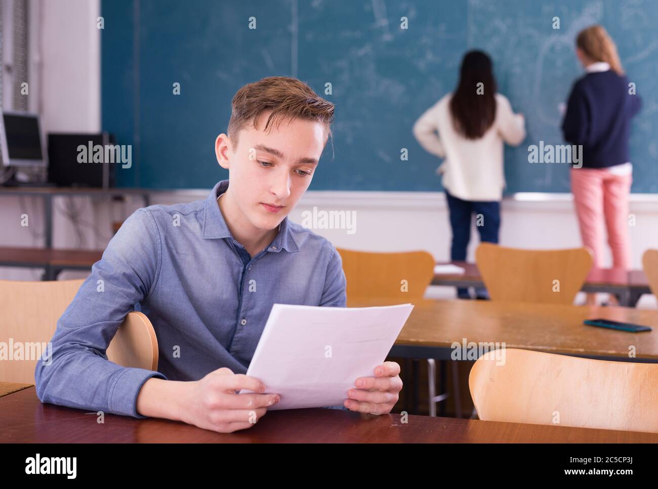 Portrait of young thoughtful guy preparing for the exam in classroom ...