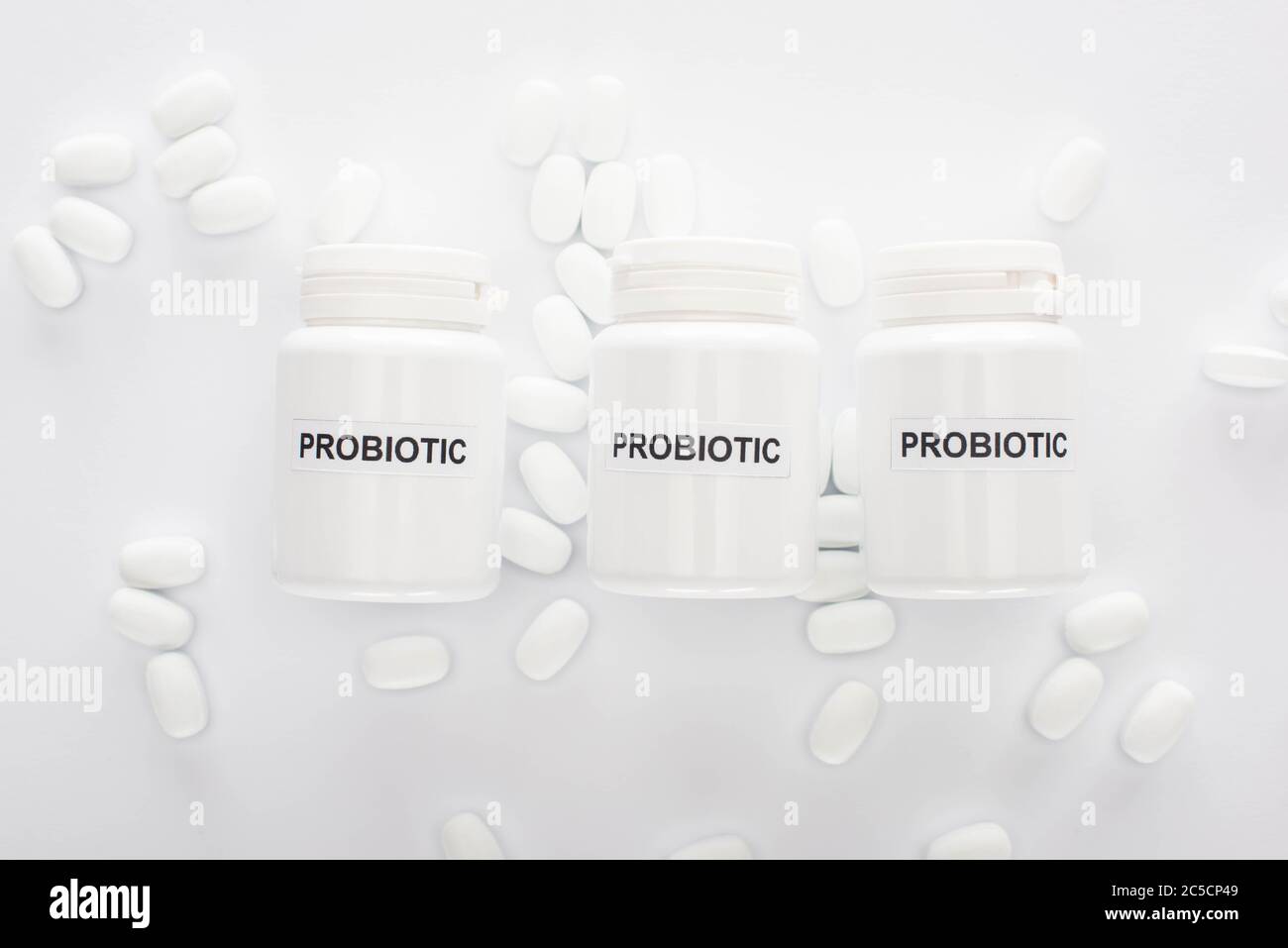 top view of containers with probiotic lettering near pills on white ...
