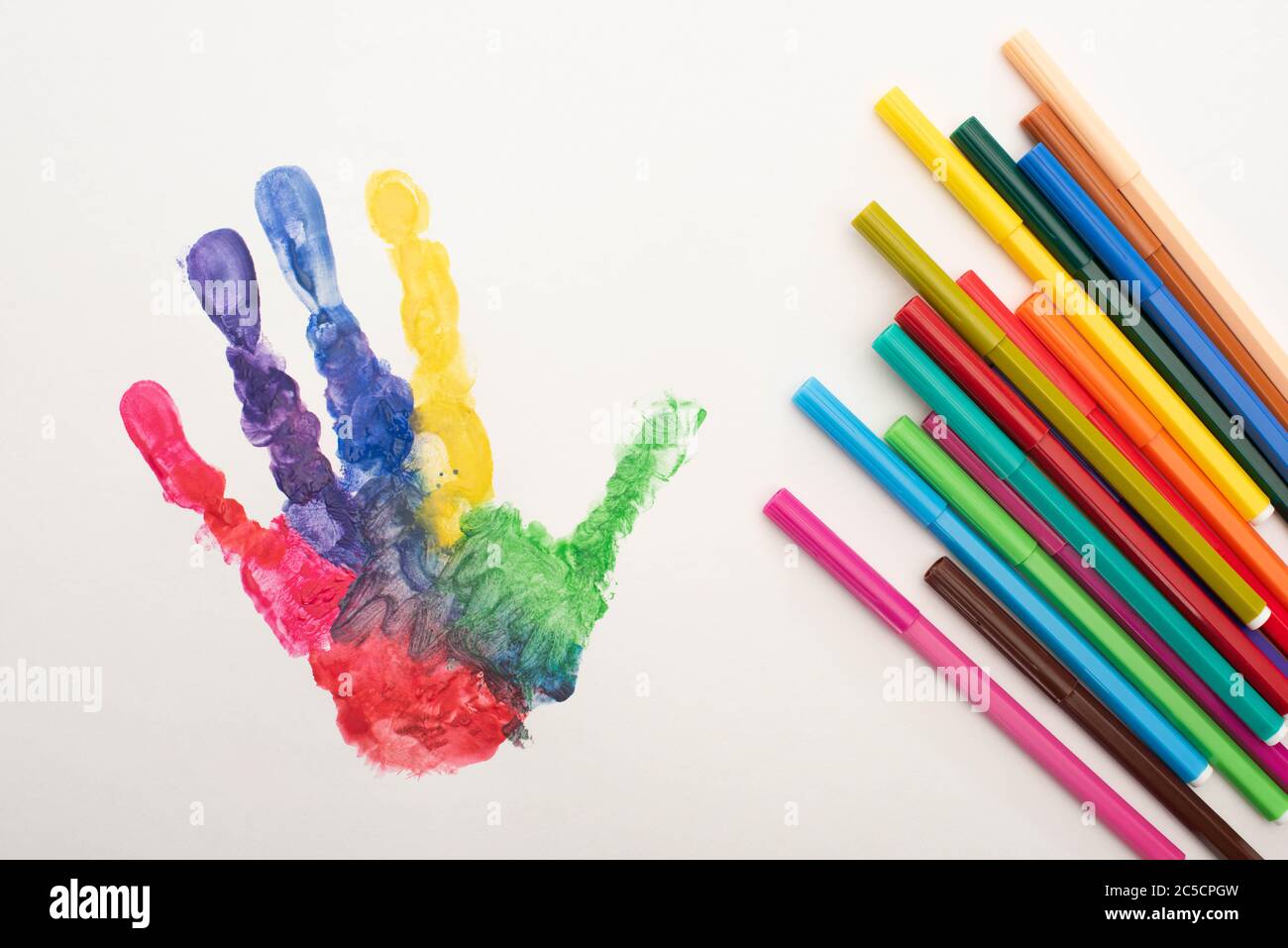 top view of colorful handprint and flat pens on white for World Autism ...