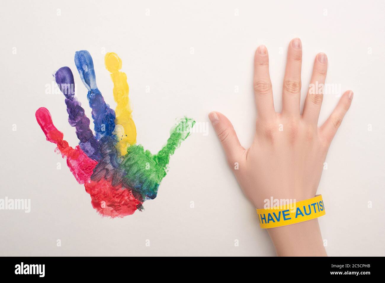 cropped view of female hand with autism bracelet on white with colorful ...