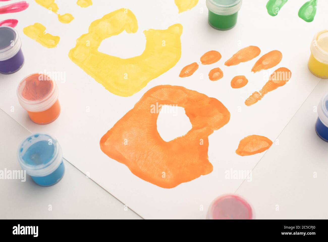 close up of colorful handprints and paints on white for World Autism ...