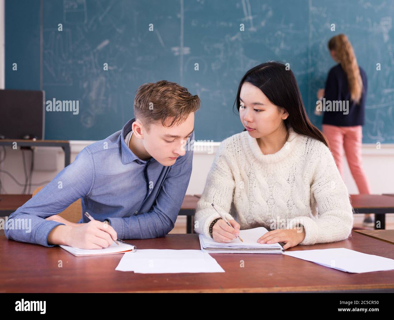 Chinese girl and male students writing notes together in audience Stock ...