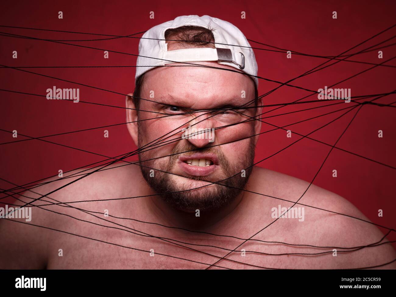 Photo of tangled in black threads fat man on red background Stock Photo ...