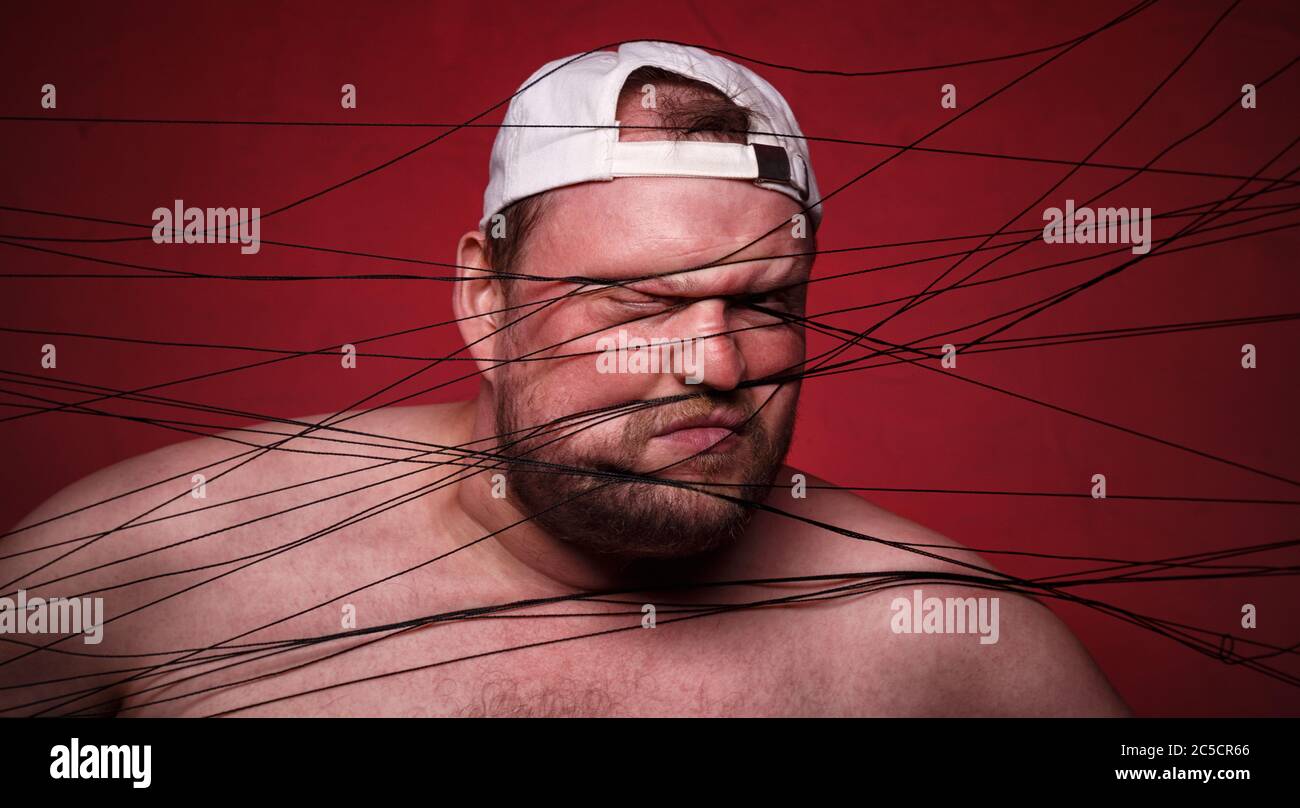 Picture of fat man tangled in black threads on red background Stock ...