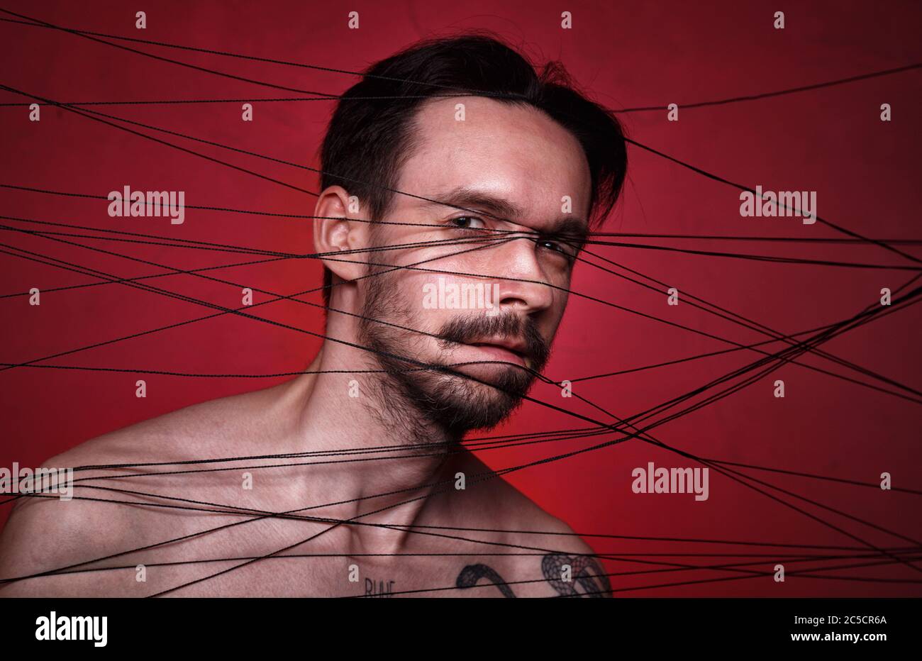 Tangled in black threads man on red background Stock Photo - Alamy