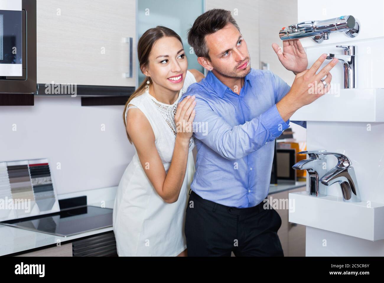 Happy young family couple looking for modern functional mixer tap in ...