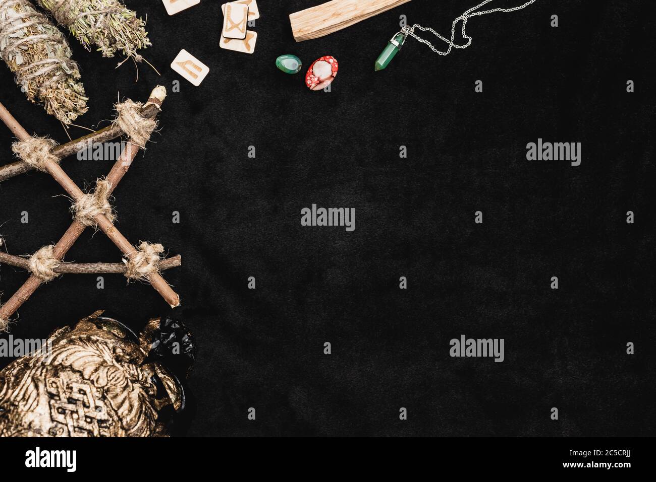 top view of runes and amulets near crystals and voodoo skull on black ...