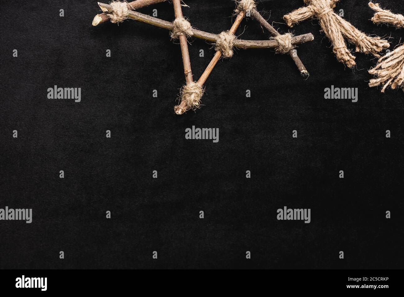 top view of voodoo doll near pentagram with wooden sticks on black ...
