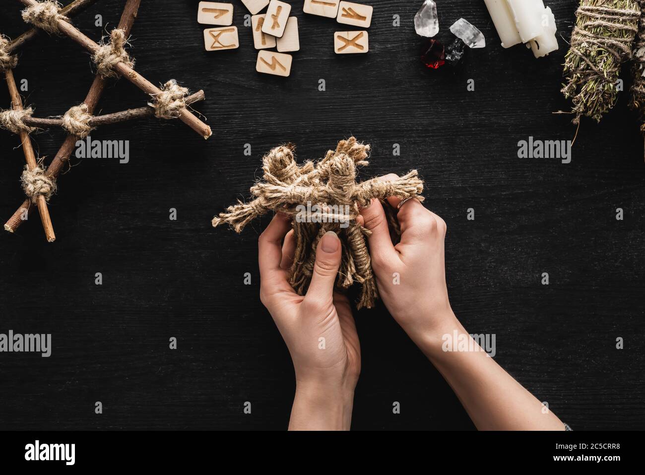 top view of woman holding voodoo dolls near scandinavian runes ...