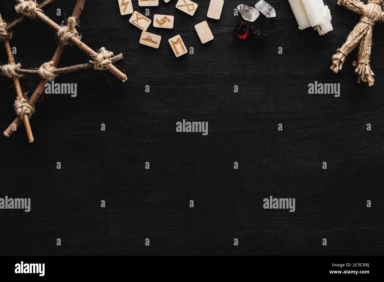 top view of runes, pentagram, candles, crystals and voodoo doll on ...