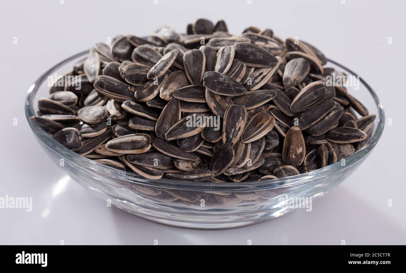 Glass bowl with sunflower seeds in hulls on white background. Popular ...