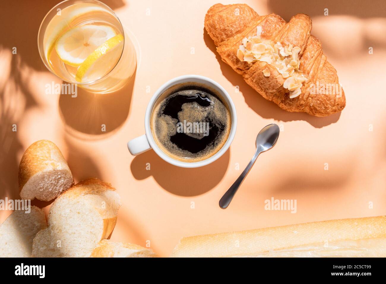 top view of coffee, water, baguette and croissant for breakfast on ...