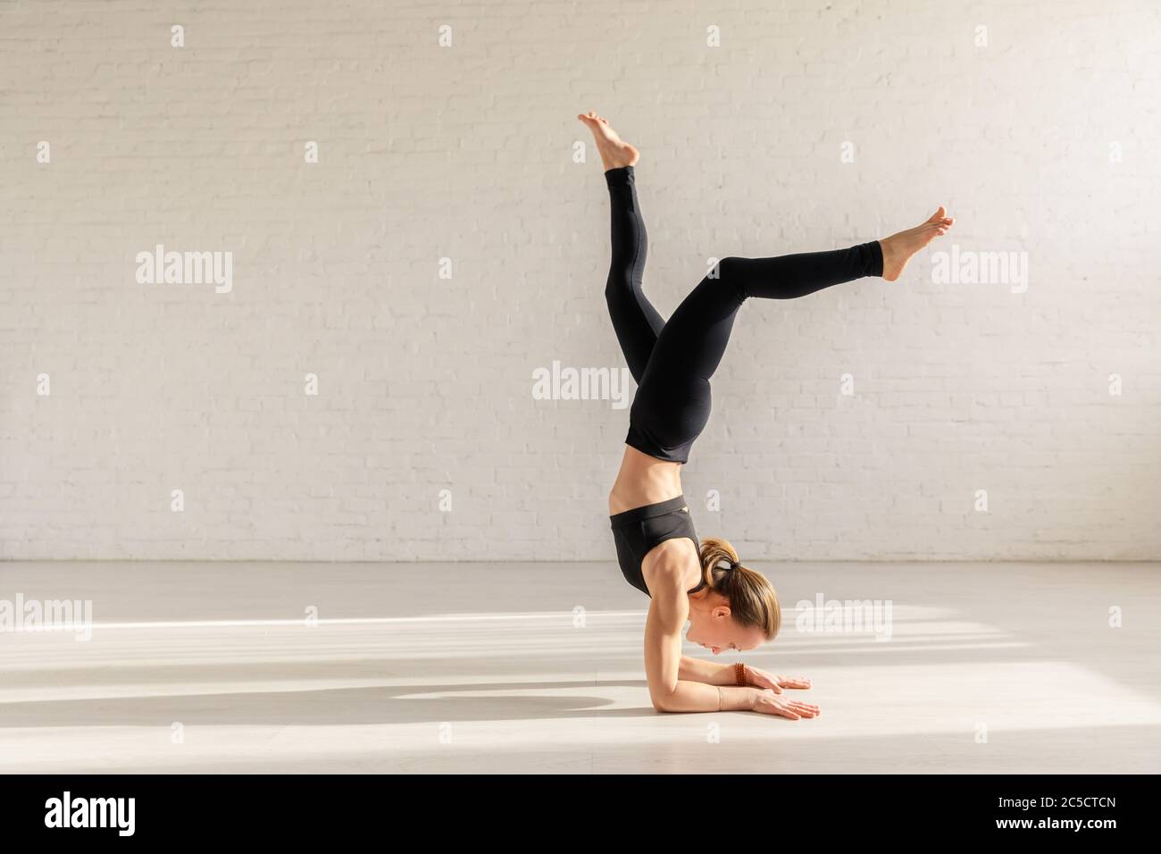 young woman doing supported headstand exercise in yoga studio Stock ...