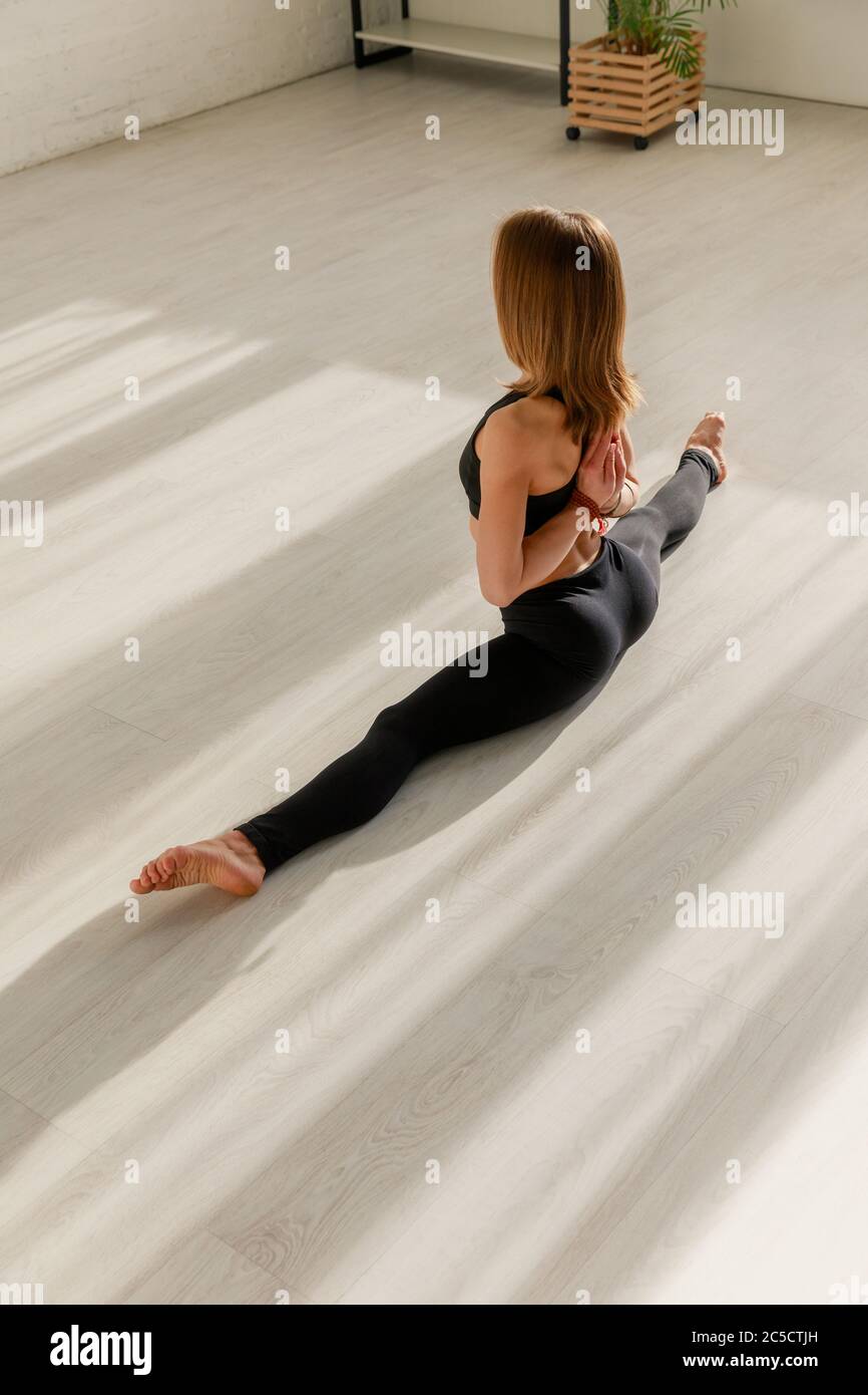 woman in reverse prayer pose doing twine stretching on floor Stock ...
