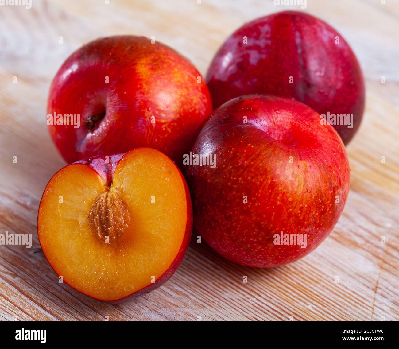 Close-up of fresh juicy red plums on wooden surface in kitchen Stock ...