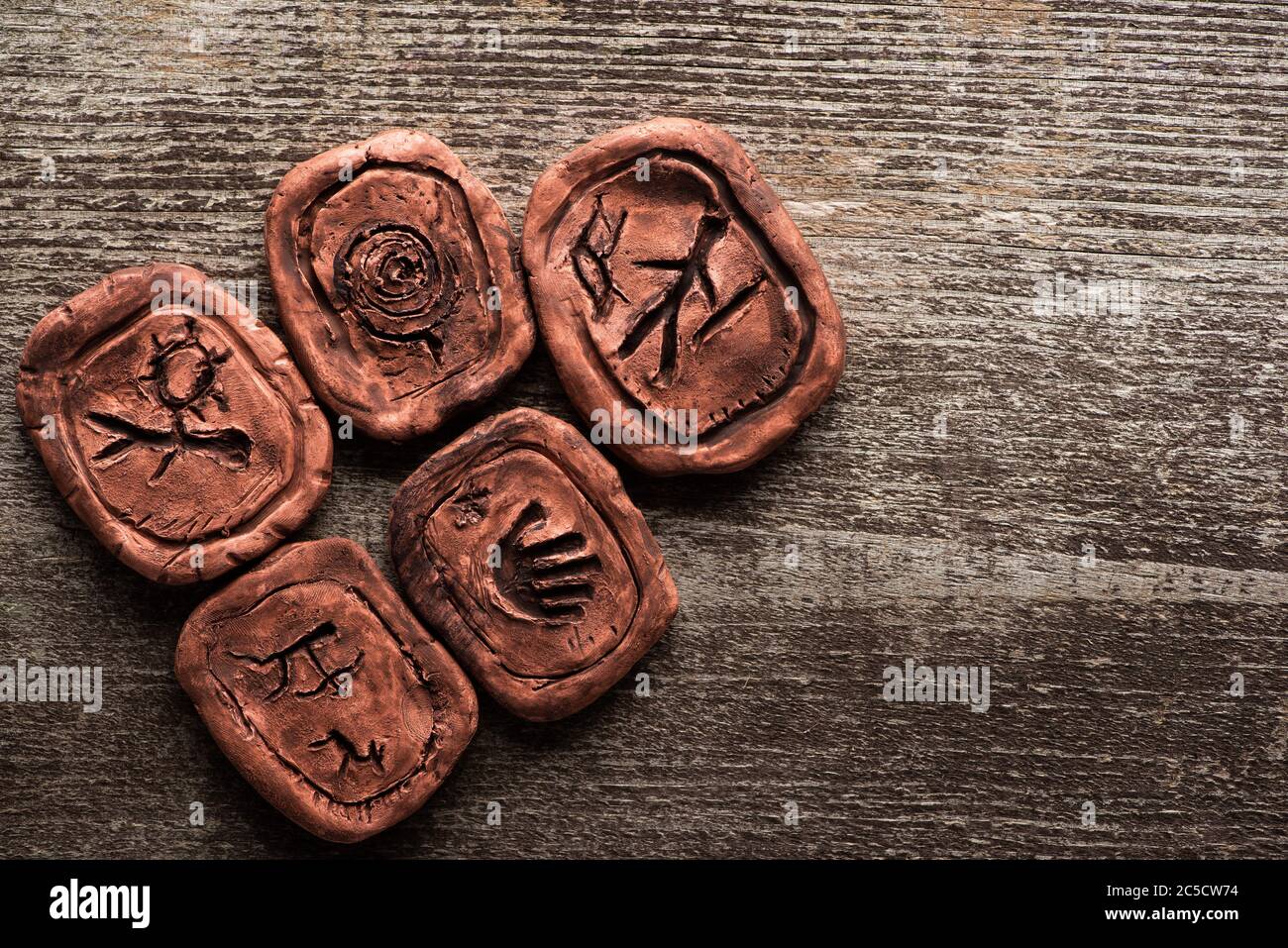 Top view of clay talismans with signs on wooden background with copy ...