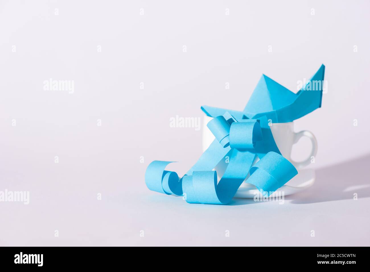 cup with paper ship near blue ribbons on white Stock Photo - Alamy