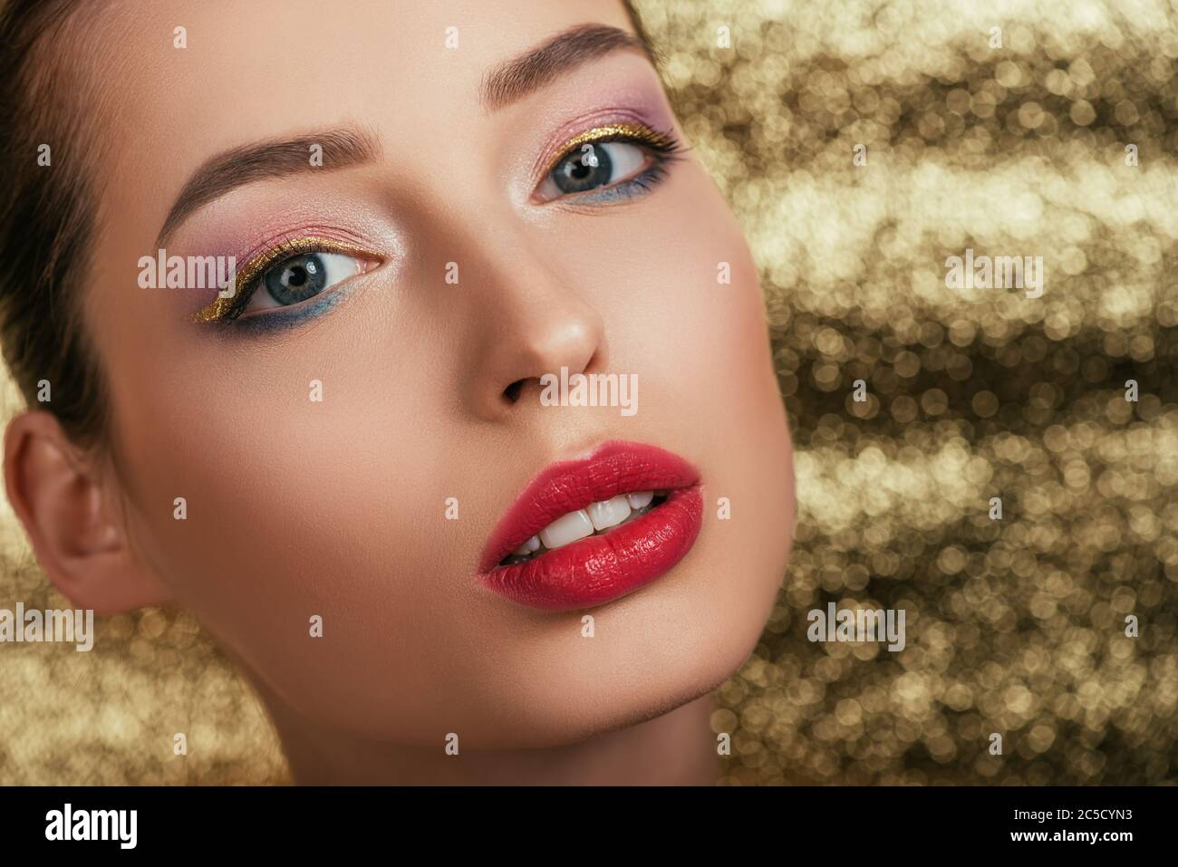 portrait of beautiful woman with shiny makeup on golden background ...
