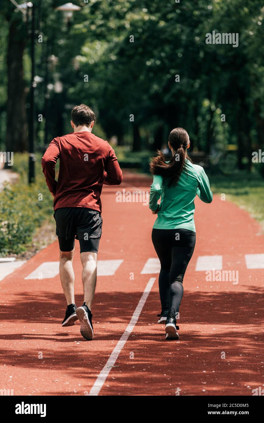 Back view of couple running on running path in park Stock Photo - Alamy