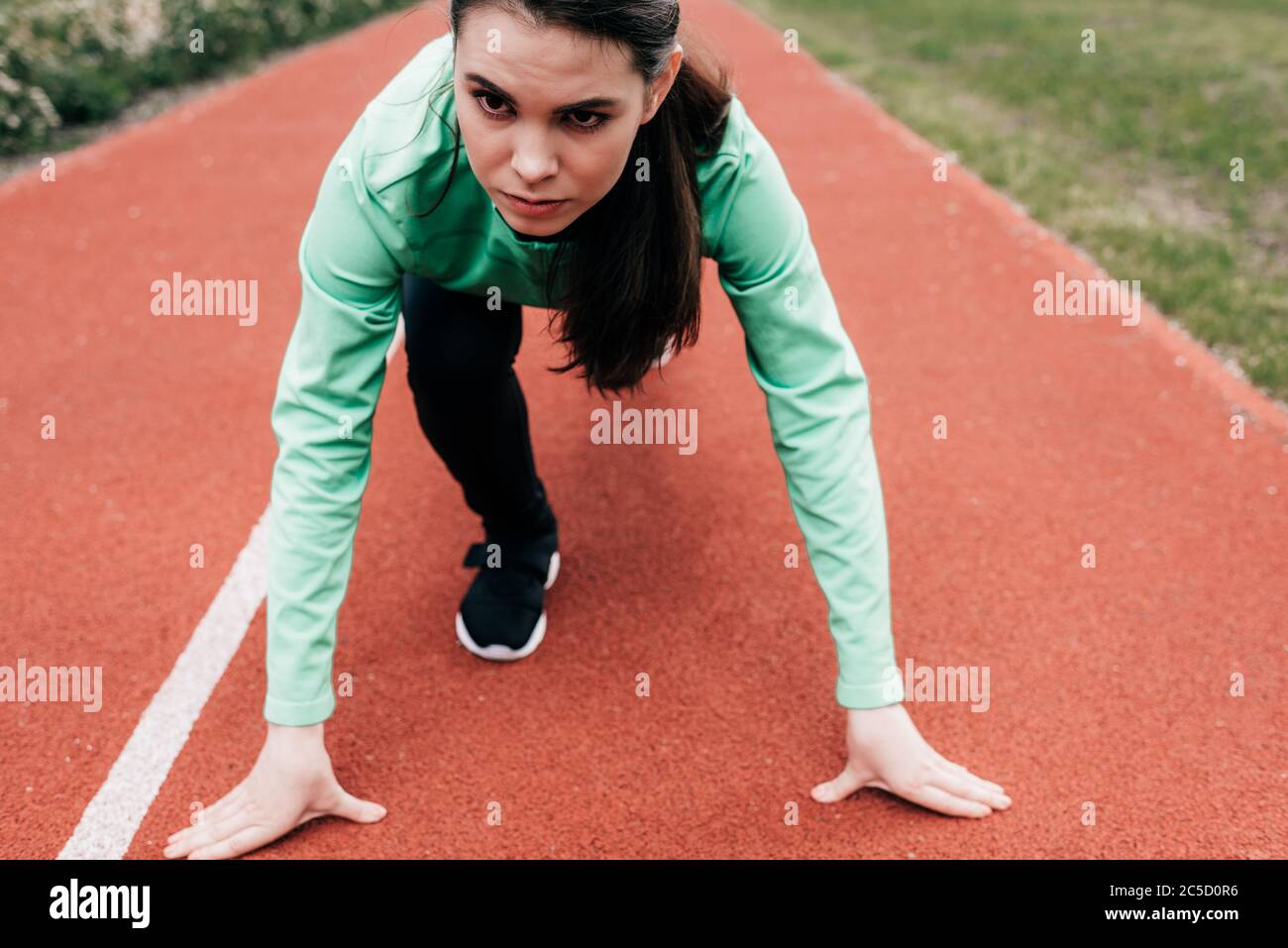 Sportswoman standing in starting position while training on running ...