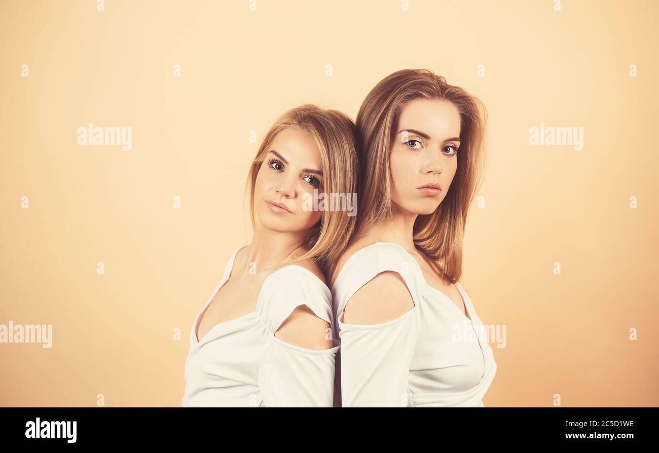 Gorgeous two caucasian sisters models posing together on beige ...
