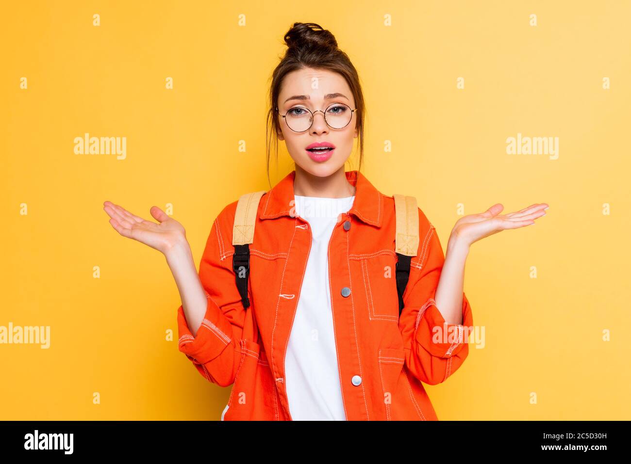 confused student in eyeglasses showing shrug gesture while looking at ...