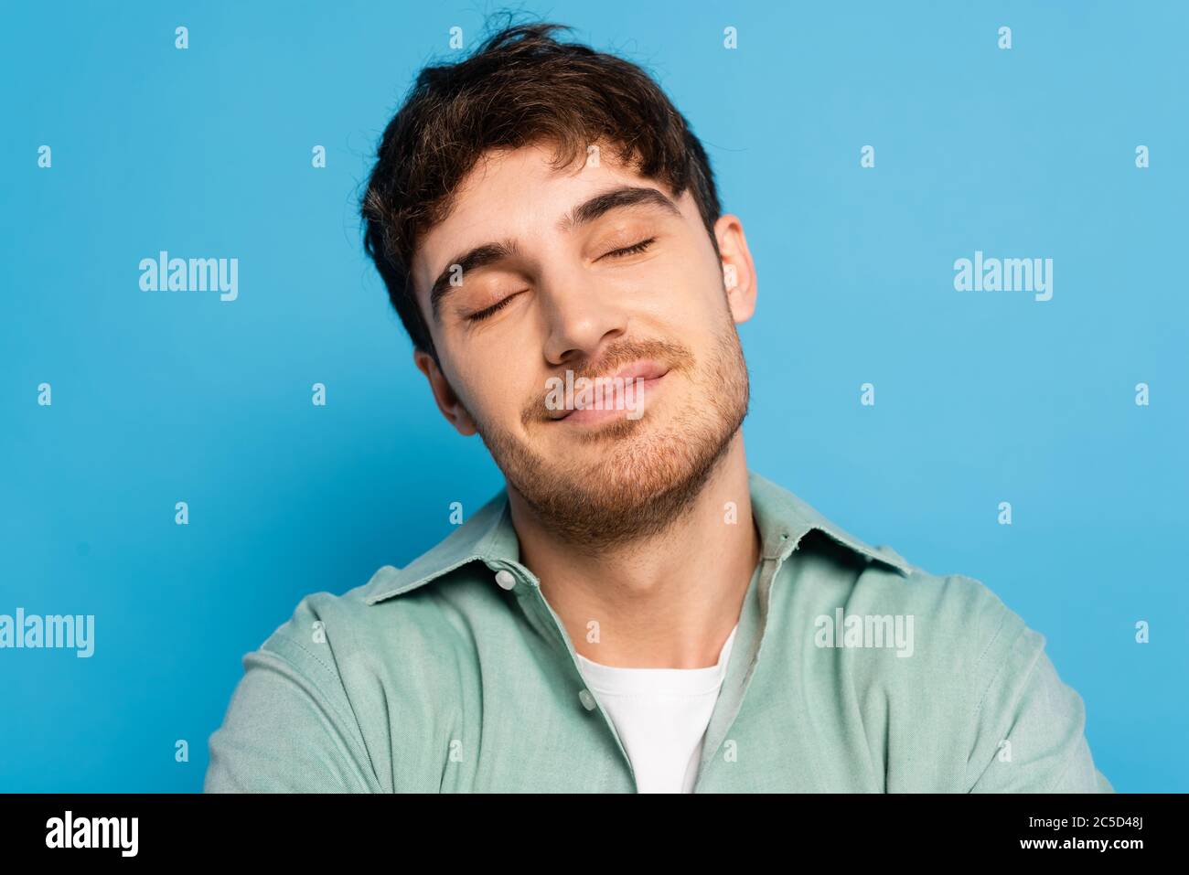 pleased young man dreaming with closed eyes on blue Stock Photo - Alamy