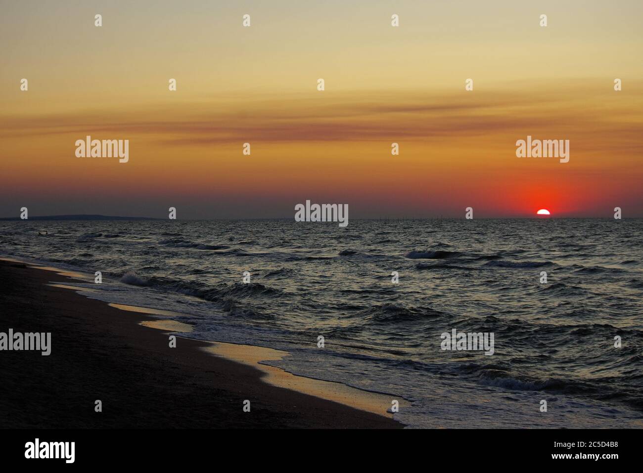 View of the red Sun setting in the sea Stock Photo - Alamy