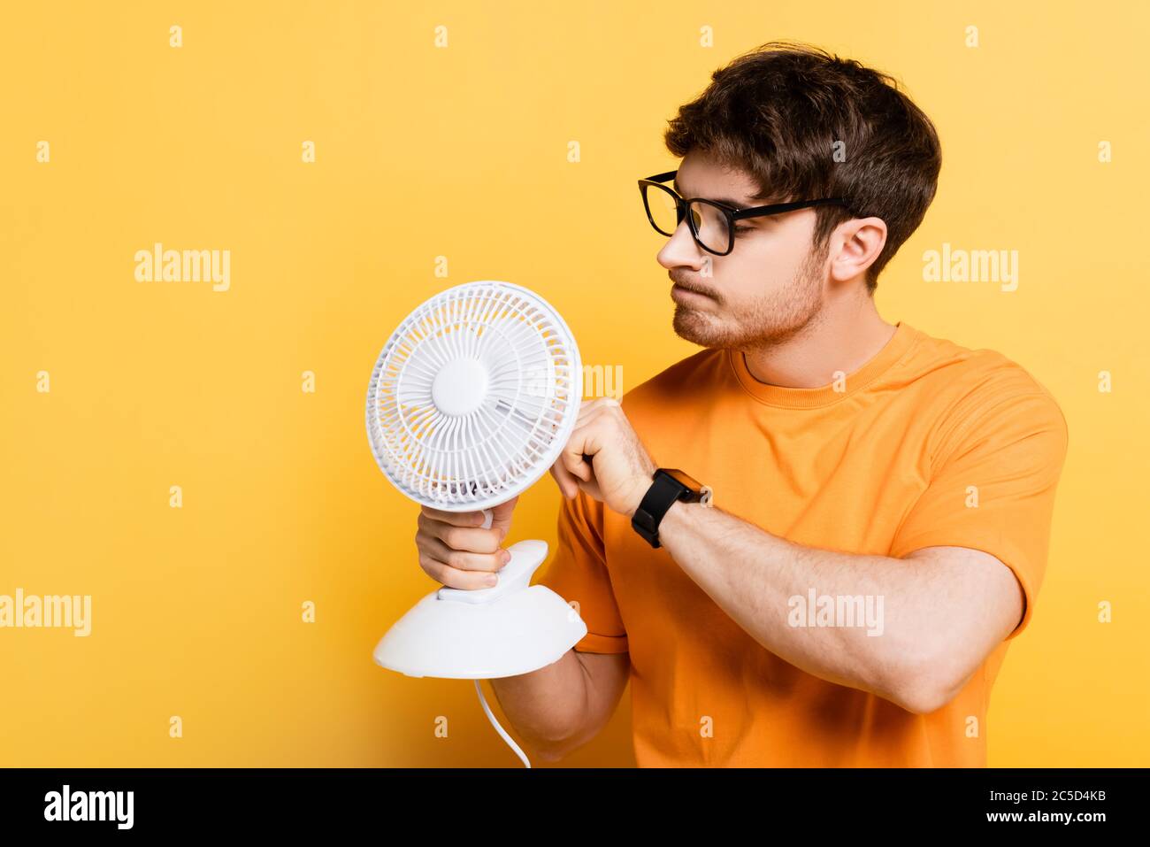 thoughtful young man fixing electric fan on yellow Stock Photo - Alamy