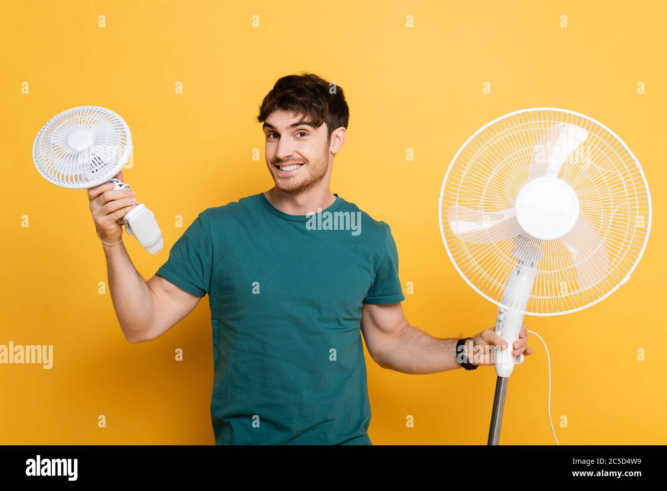 happy man standing with two electric fans on yellow Stock Photo - Alamy