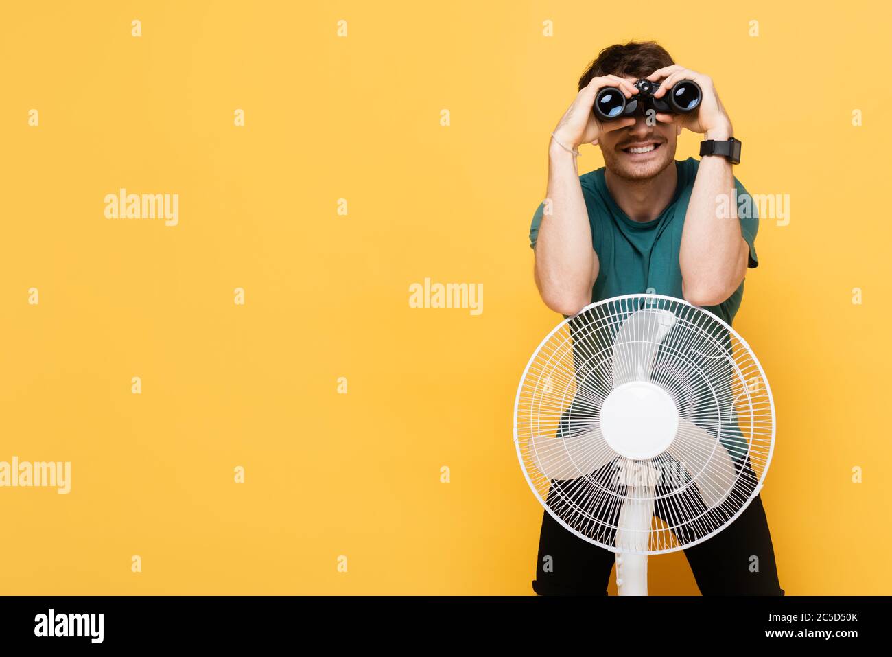 cheerful man looking through binoculars while standing with electric ...