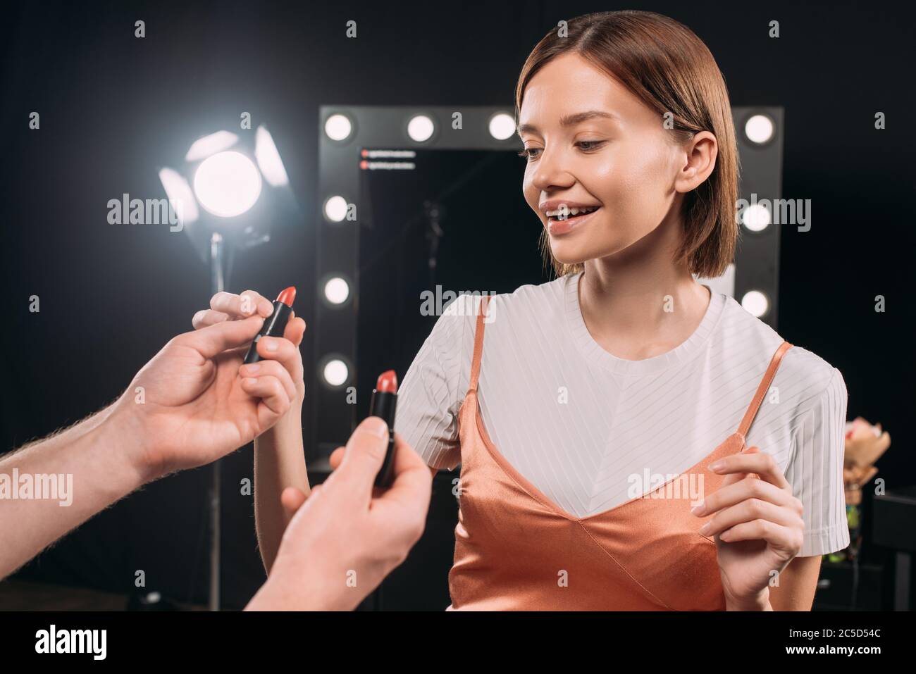 Smiling model taking lipstick from makeup artist in photo studio Stock ...