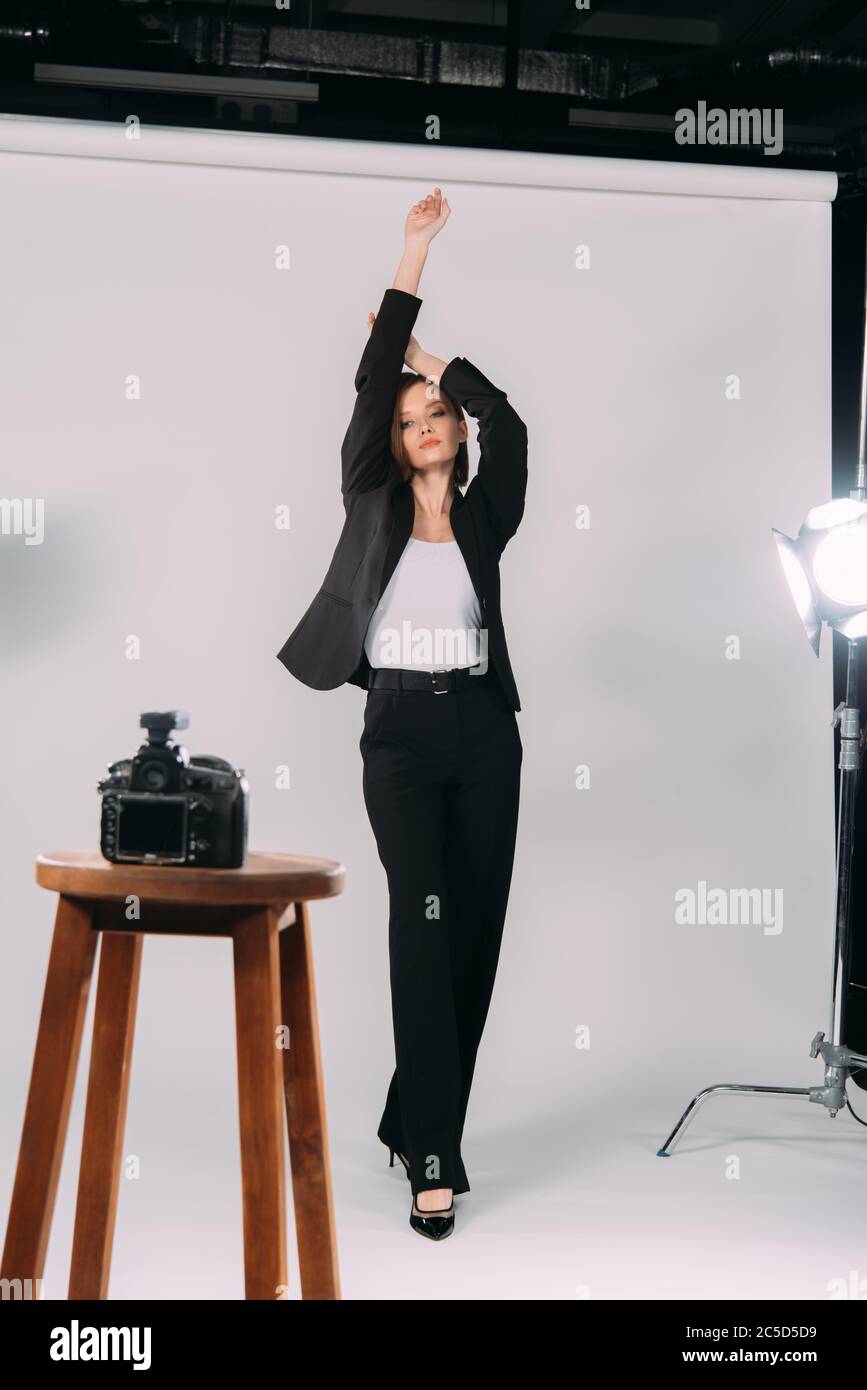 Attractive model in formal wear posing at digital camera on chair in ...