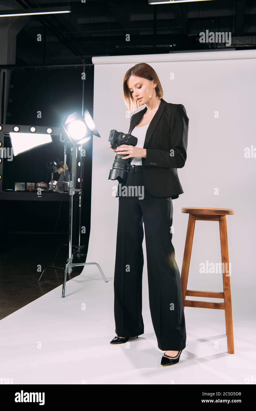 Beautiful model looking at display of digital camera in photo studio ...