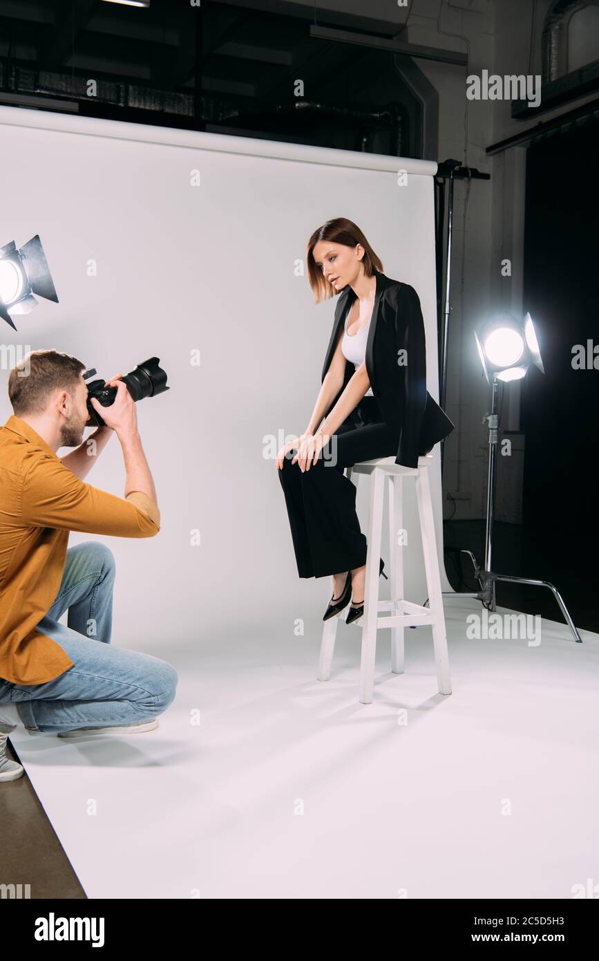 Side view of beautiful model sitting on chair while posing at ...