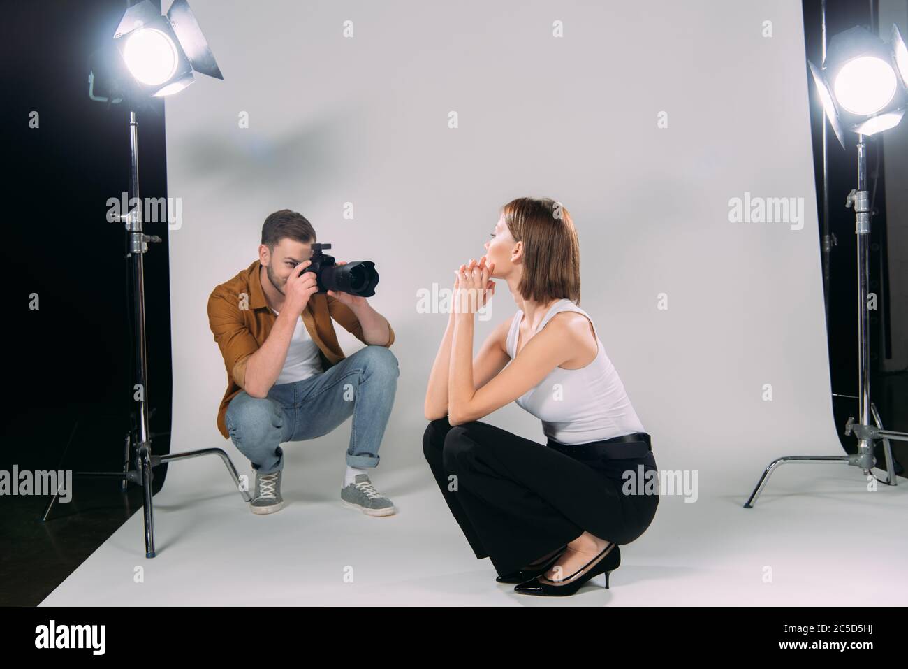 Photographer taking photo of attractive model in photo studio Stock ...