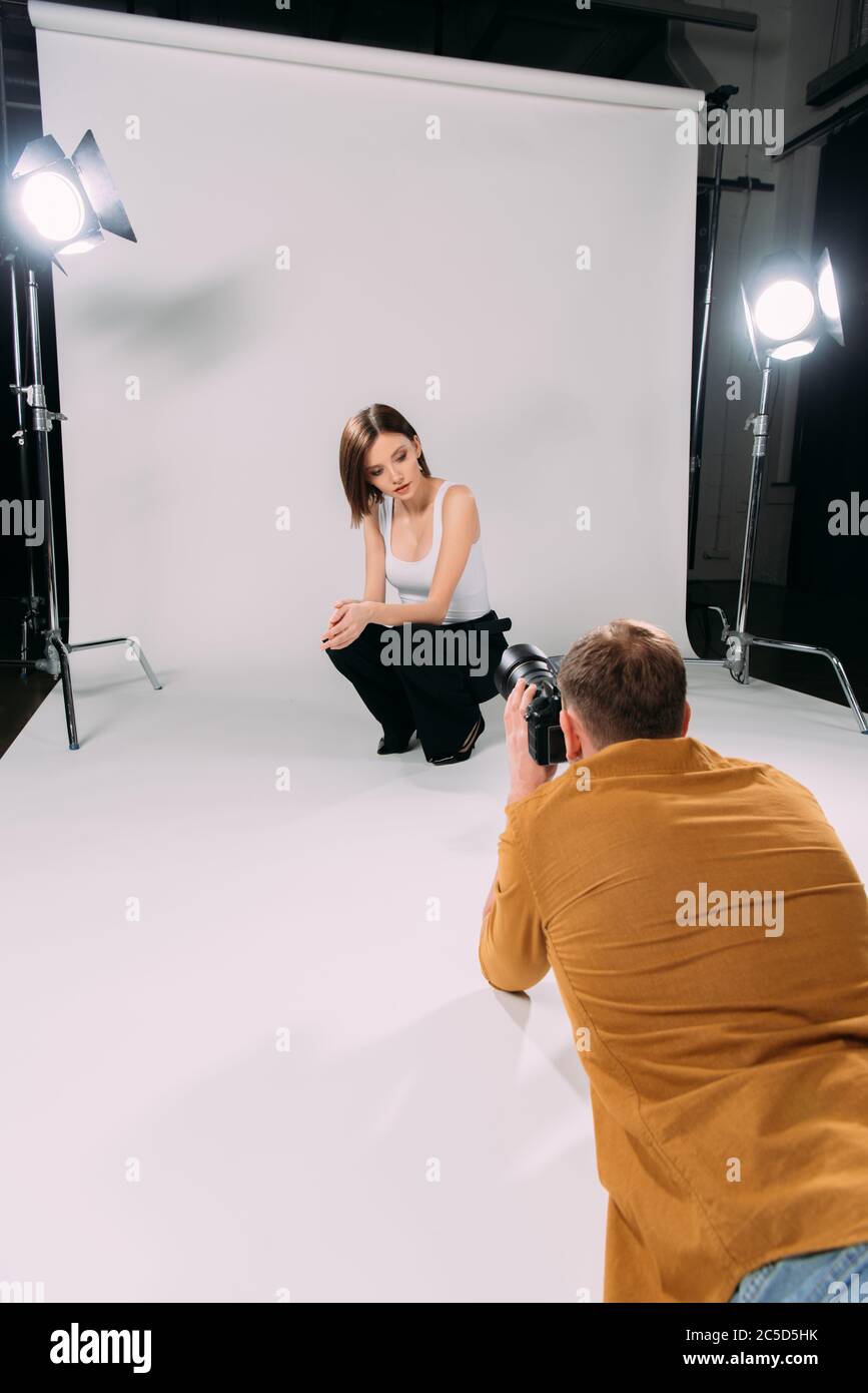 Attractive model posing while working with photographer in photo studio ...