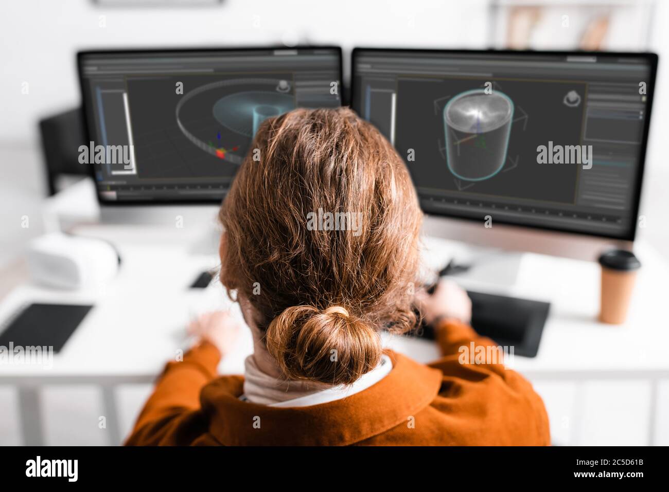 Back view of digital designer using graphics tablet and computers while ...