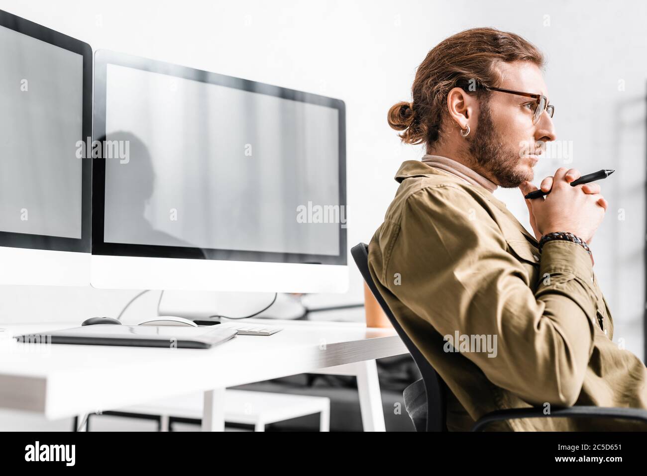 Side view of handsome 3d artist holding stylus of graphics tablet and ...