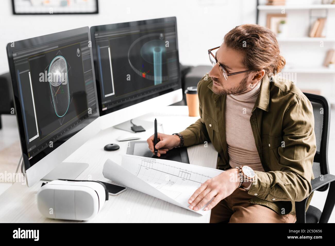 3d artist using blueprint with graphics tablet and computers while ...