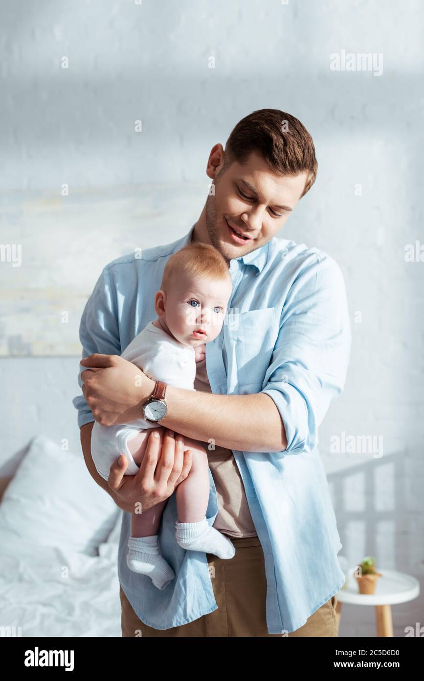 happy father holding adorable infant on hands in bedroom Stock Photo ...