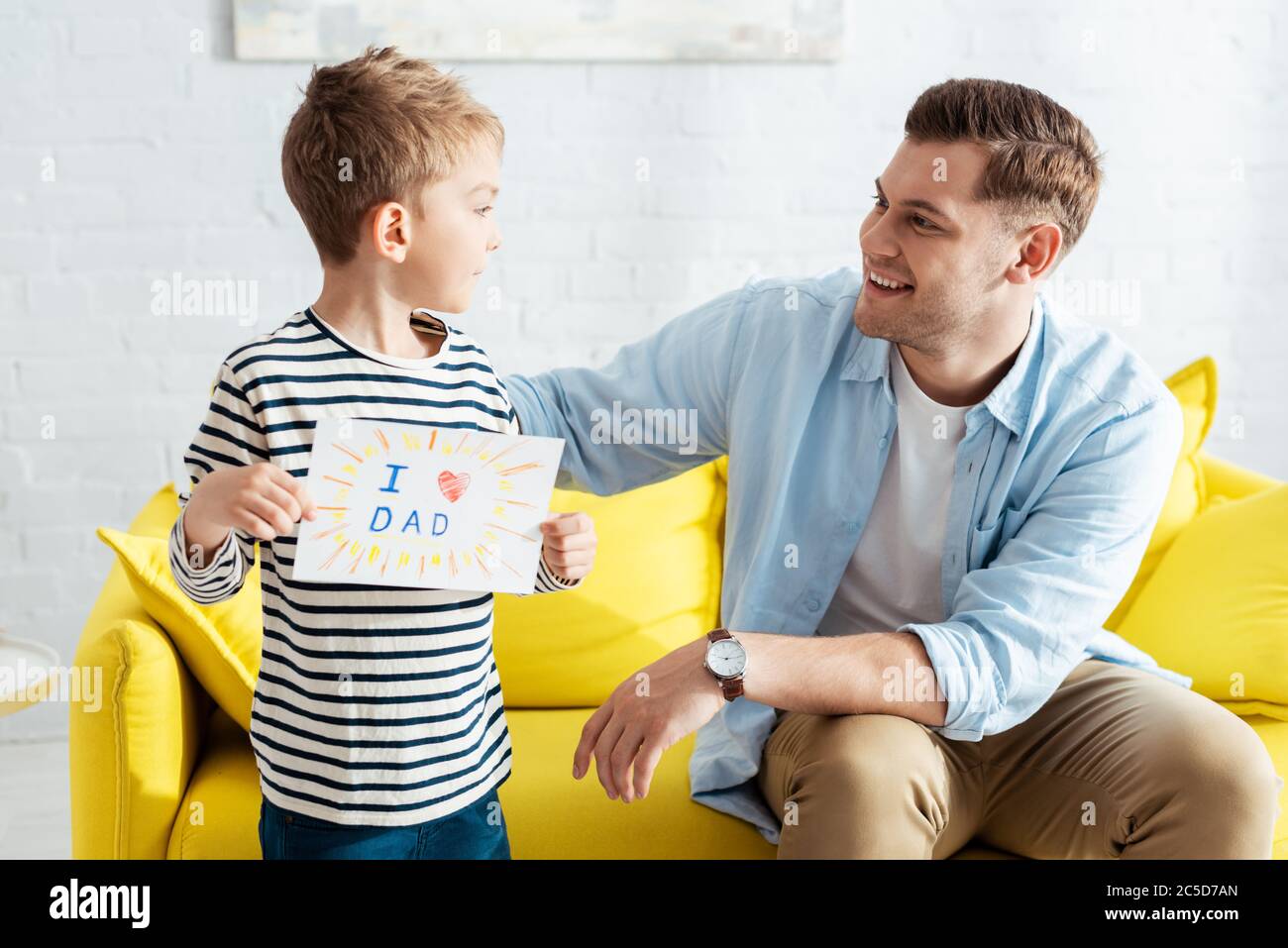 happy father looking at son holding fathers day greeting card with ...