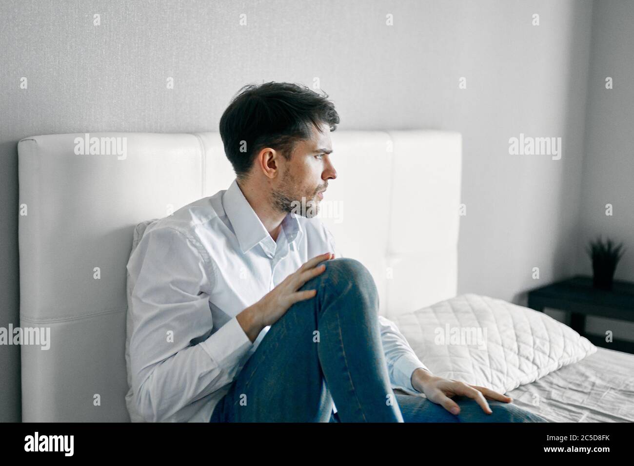 sad man sitting in bed indoors and looking aside loneliness Stock Photo ...