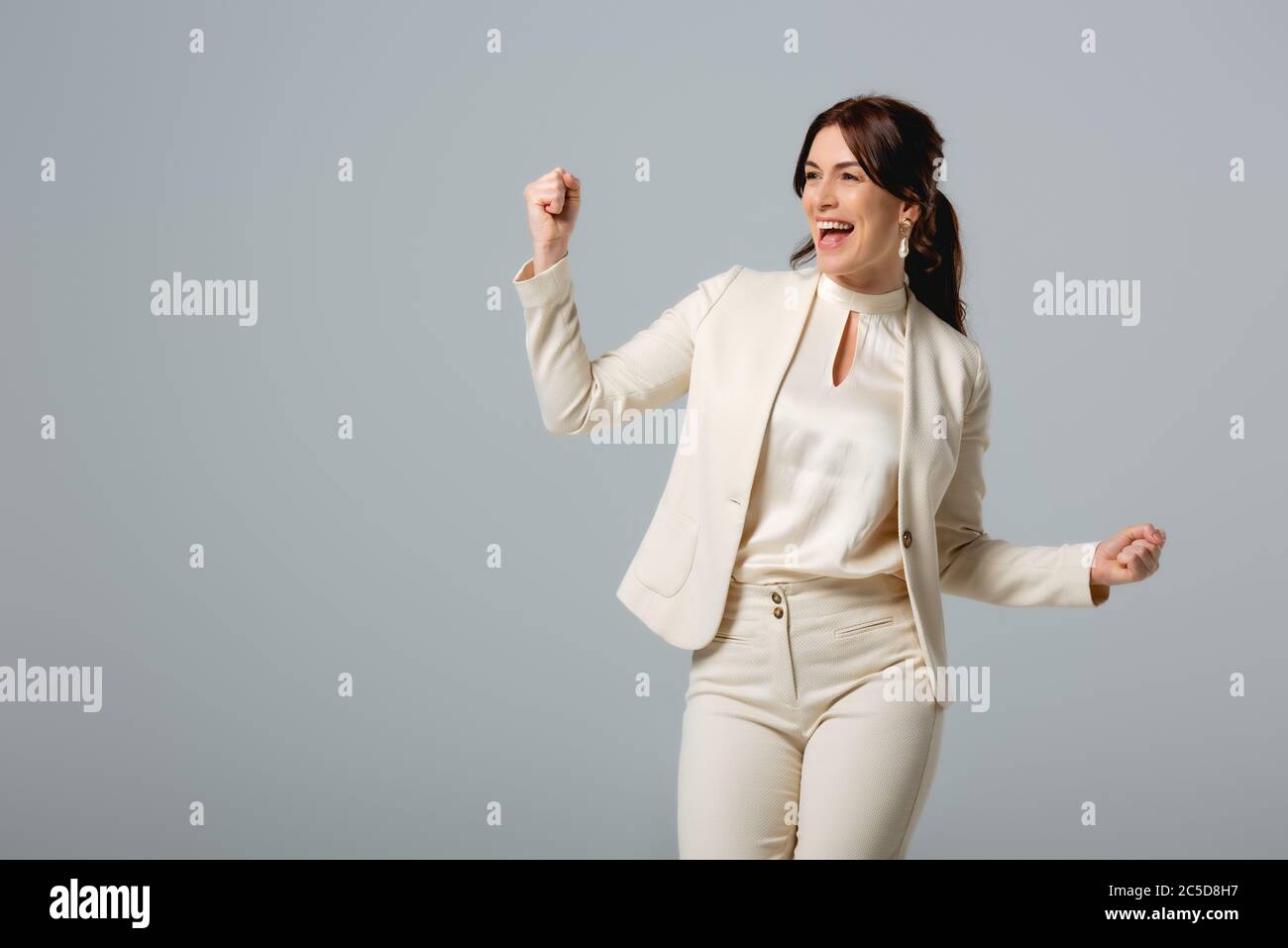 Positive businesswoman showing yeah gesture isolated on grey, concept ...